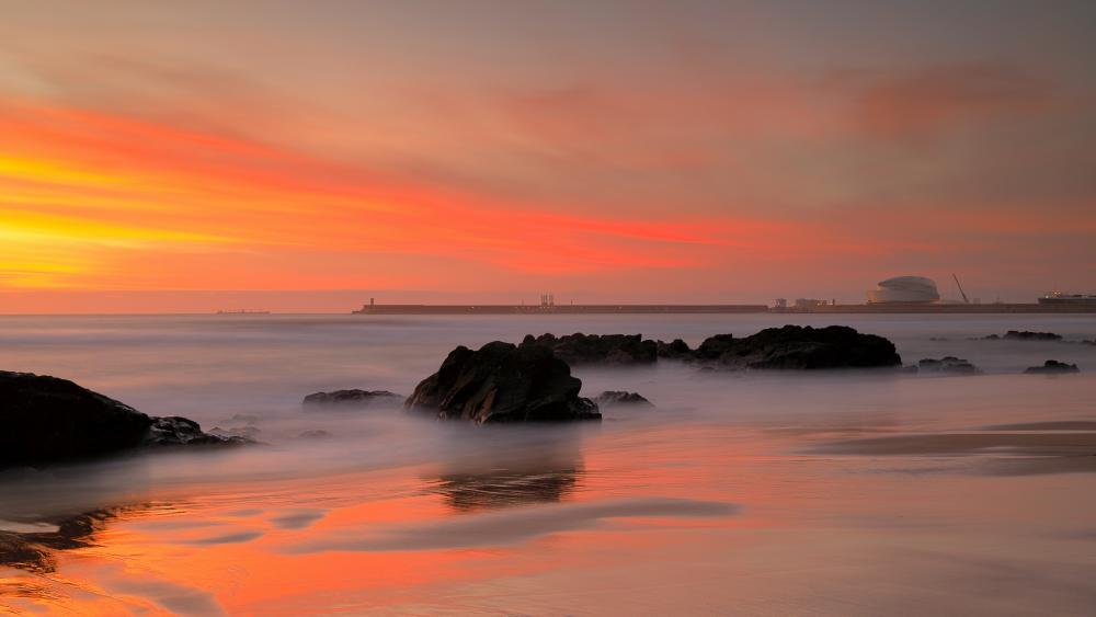 Fiery Sunset Over Rocky Beach Horizon in Smooth Long Exposure - backiee