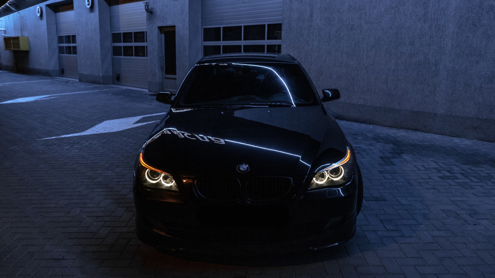 Sleek BMW E60 Dimly Lit in Urban Garage - backiee