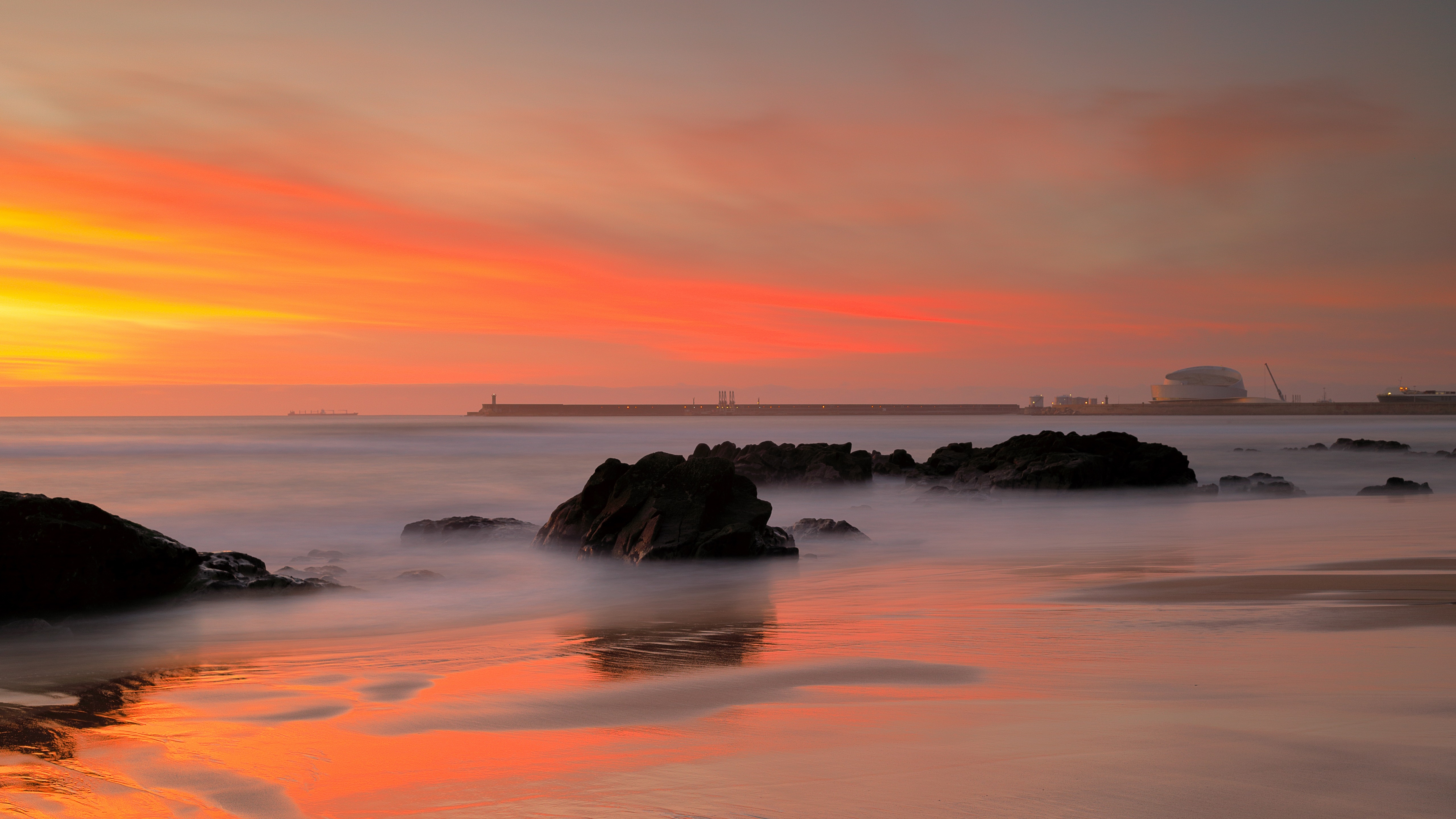 Fiery Sunset Over Rocky Beach Horizon in Smooth Long Exposure - backiee