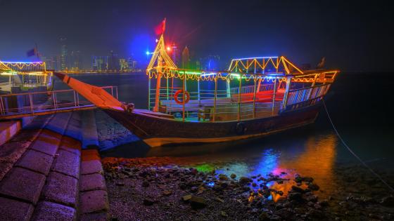 Colorful illuminated dhow boat at night - Doha, Qatar - backiee